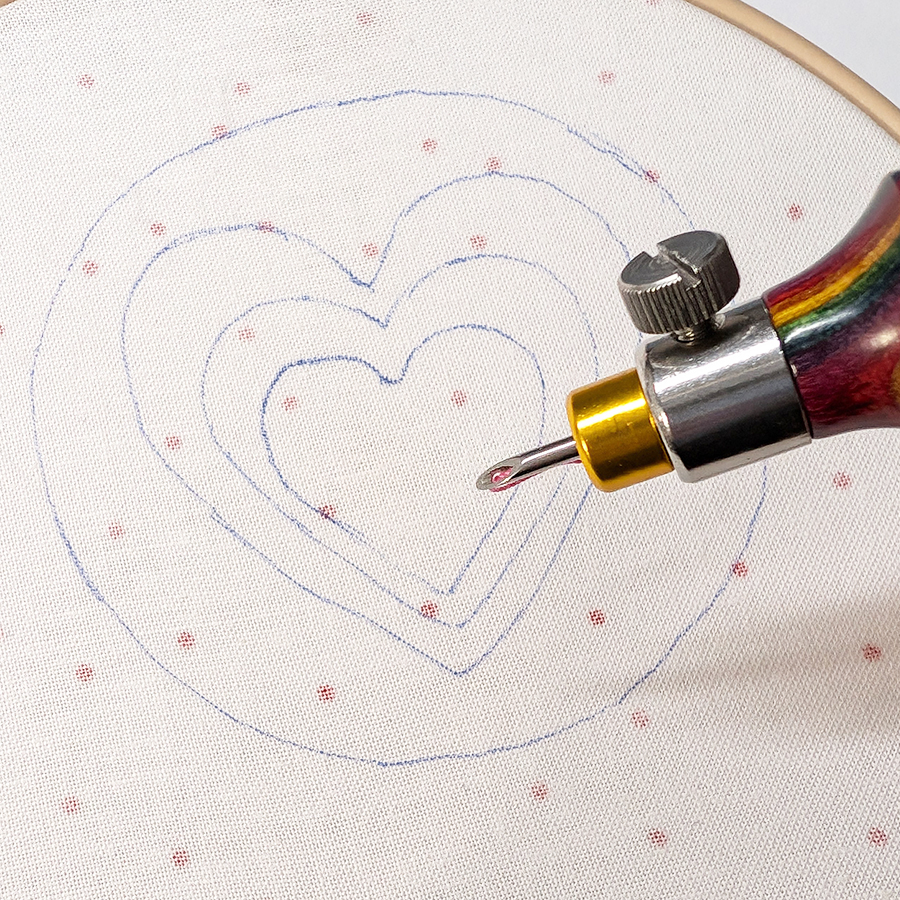 A tool creating a heart pattern on a fabric with dots. - Sulky