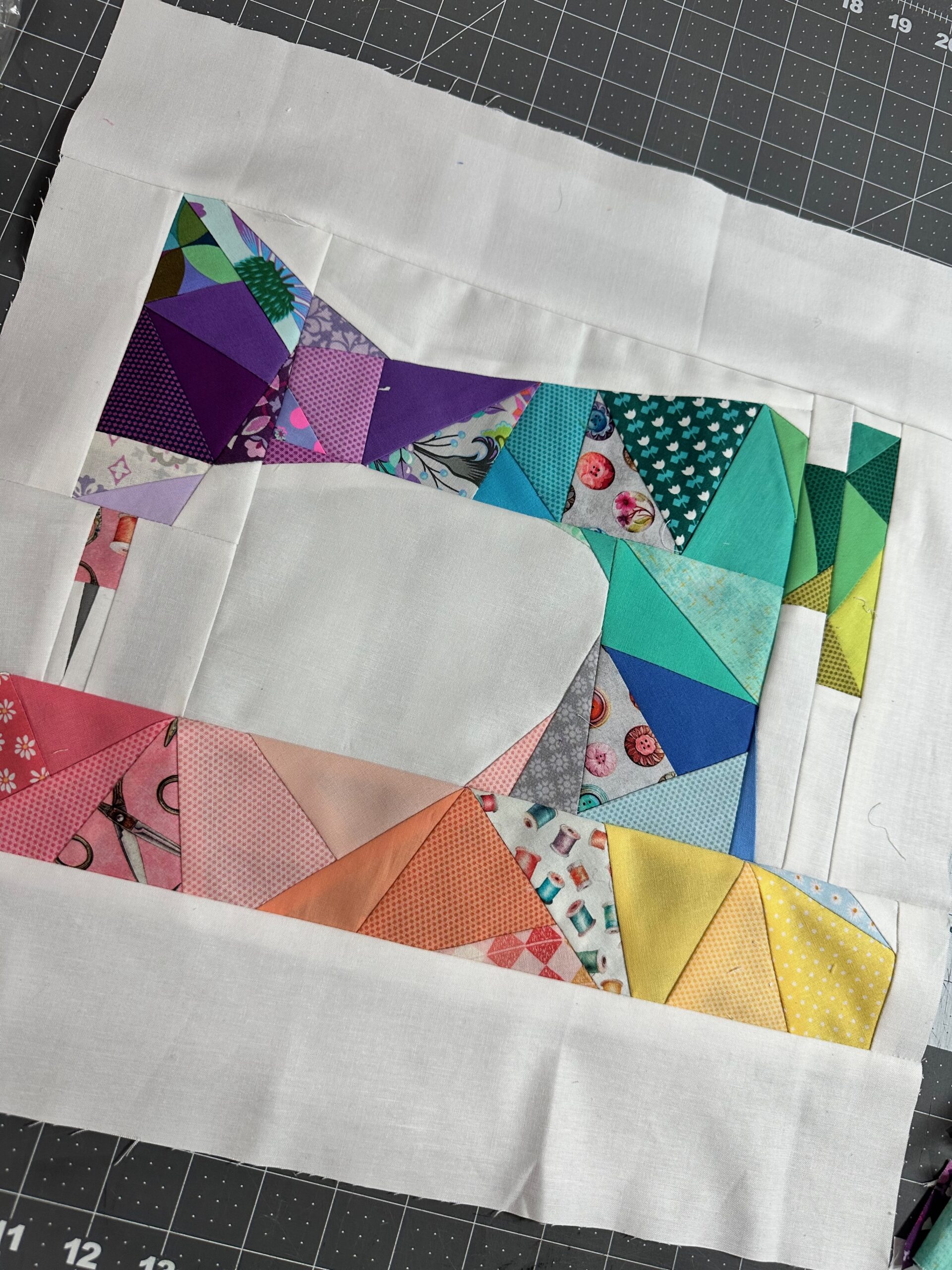 Colorful patchwork quilt block on a sewing machine fabric base. - Sulky