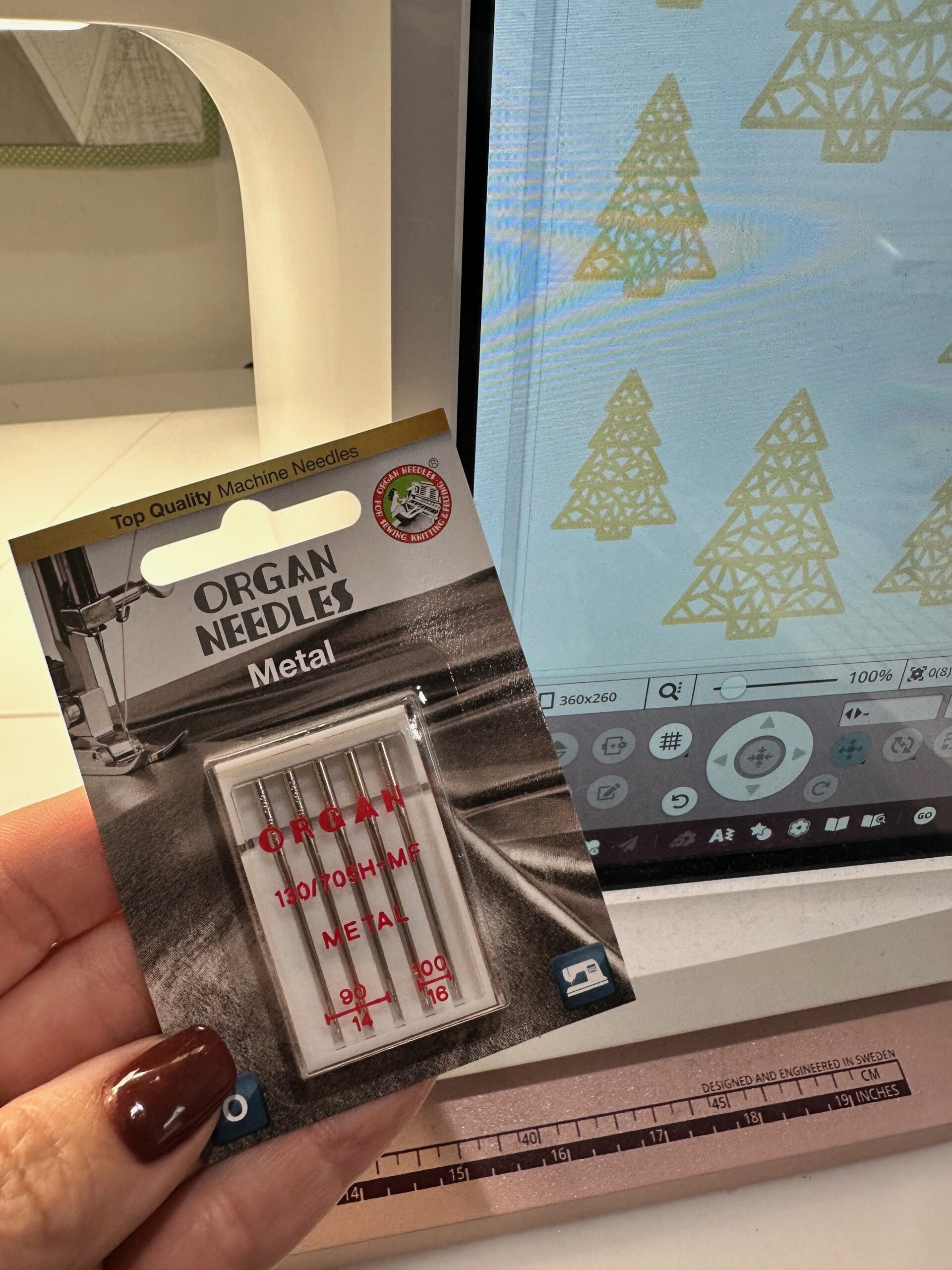 A hand holding a pack of red and white needles in front of a computer ...